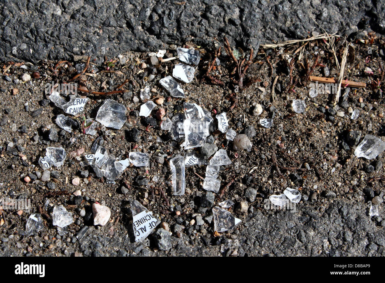Shards of broken glass scattered on a pavement, showing sharp edges and ...