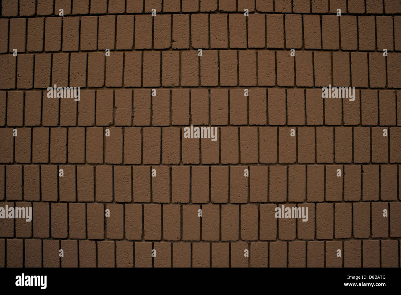 A close-up photo of a brown brick wall with vertical bricks arranged in ...