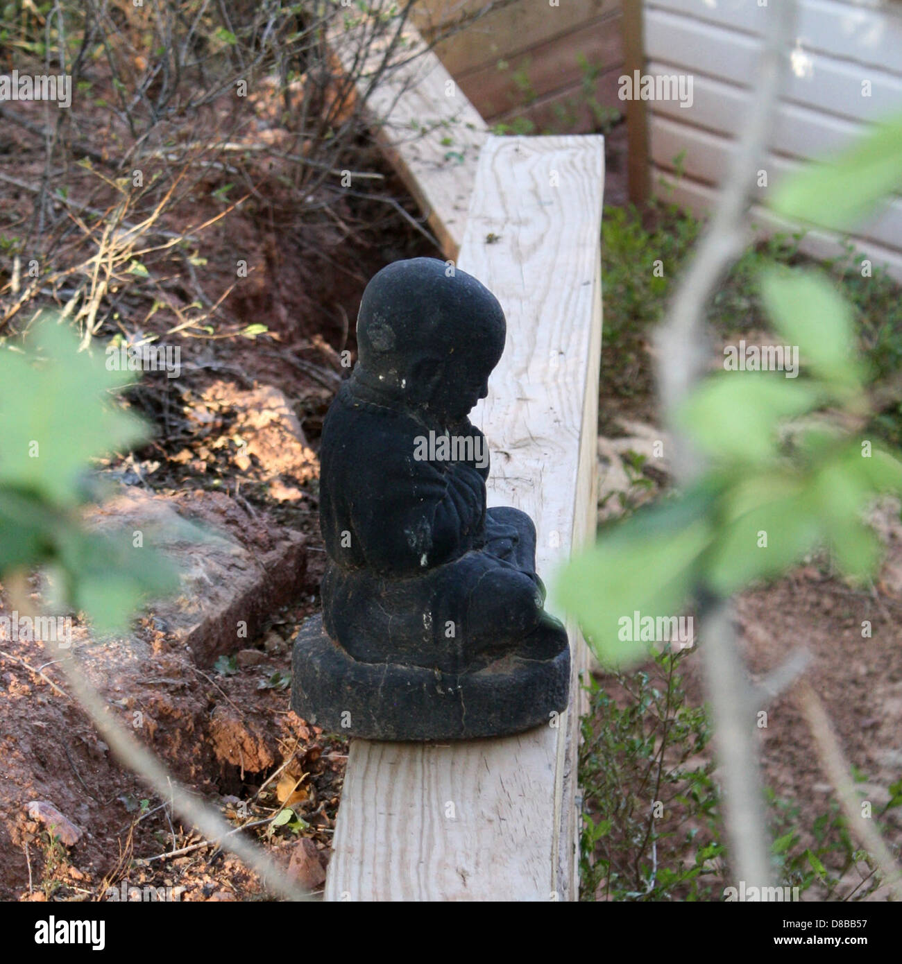 A Buddha statue rests on an outdoor retaining wall, symbolizing peace ...