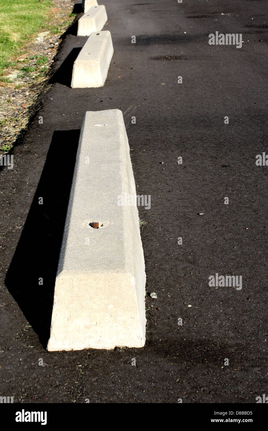 A set of cement parking stops arranged in a parking lot, used to guide ...