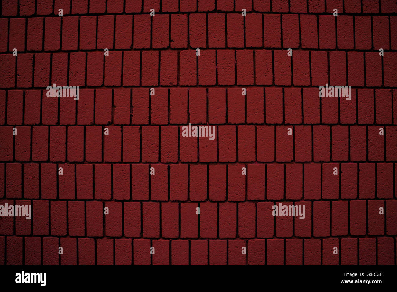 This stock photo shows a dark red brick wall with vertical bricks ...
