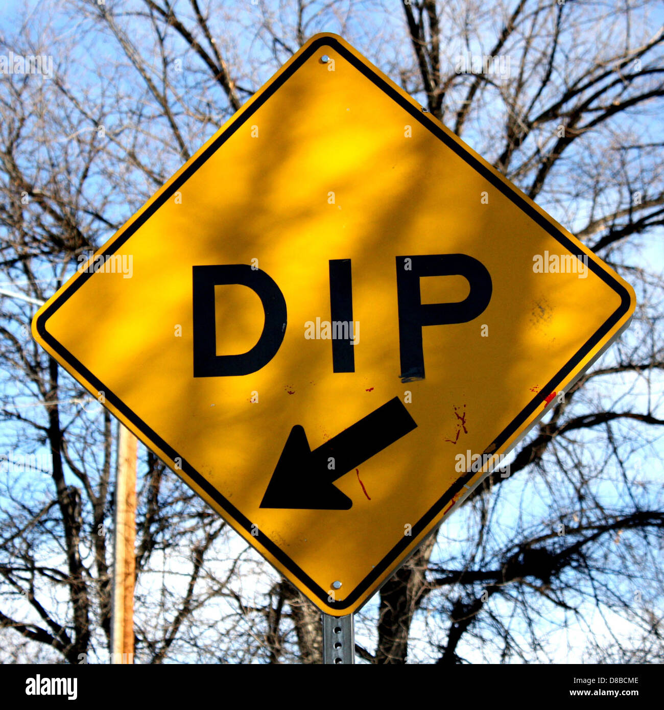 A road sign indicating a dip ahead, marked with an arrow to direct ...