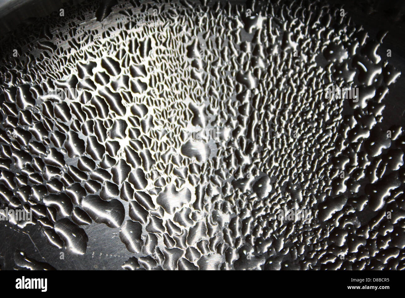 Close-up of water droplets on a metal surface, showing the contrast ...