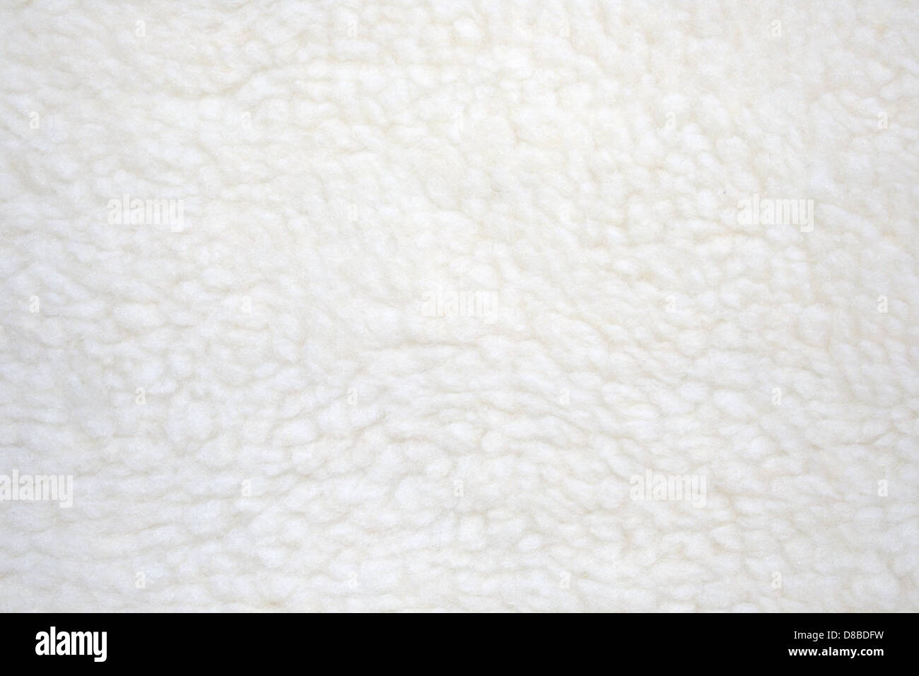 A close-up of natural cream-colored faux sherpa wool fabric, showcasing ...