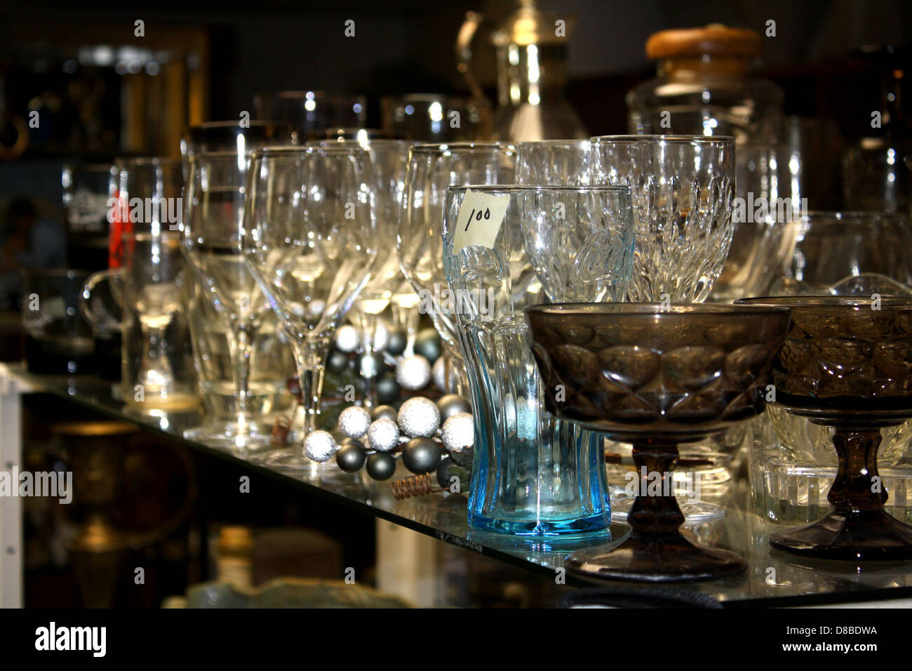 A collection of glassware is displayed on shelves in a thrift shop. The ...