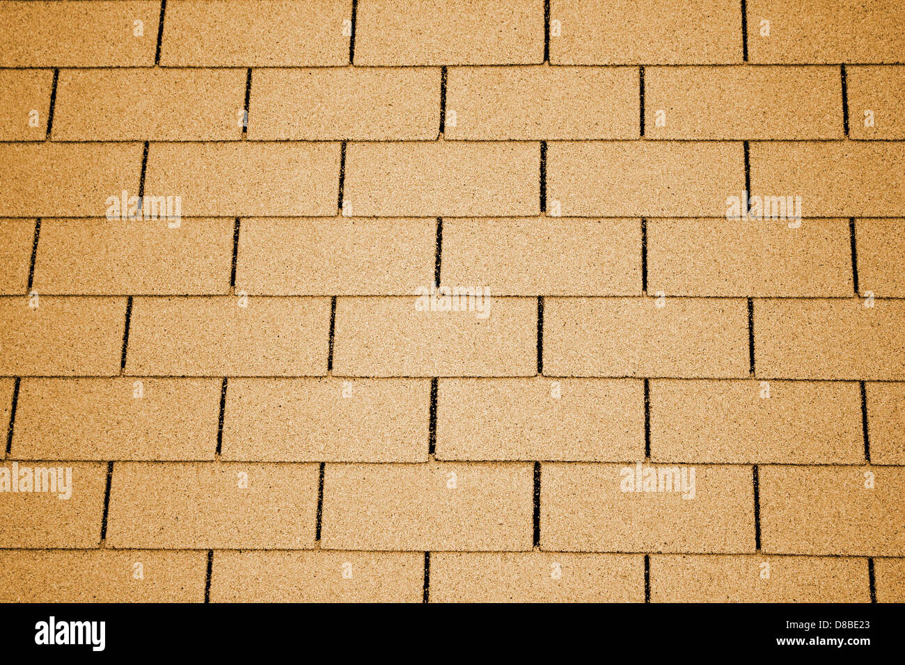 A close-up view of golden tan asphalt roof shingles, highlighting their ...