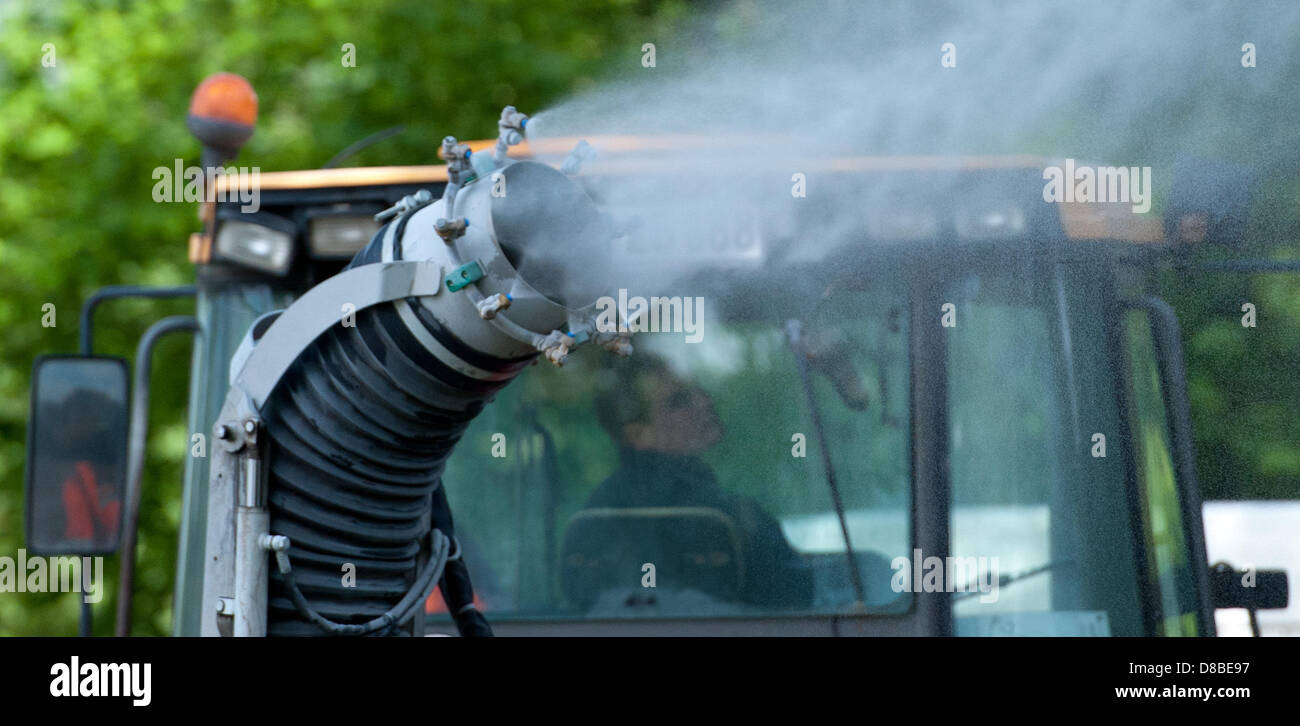 A pest controller sprays insecticide from a tractor onto oak trees to ...