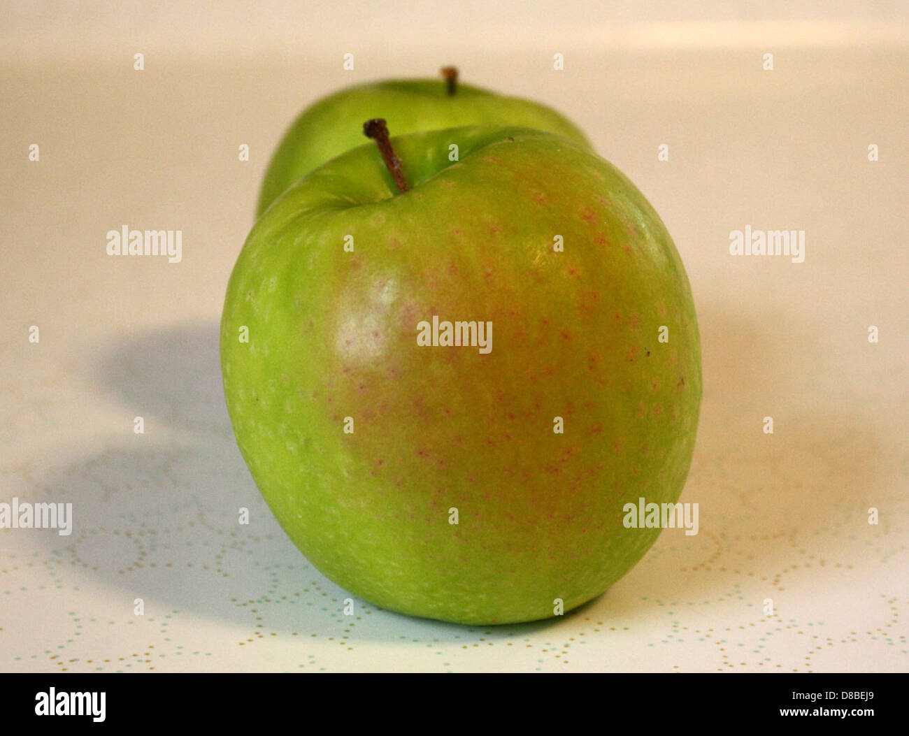 A fresh green apple with a glossy skin, reflecting light and displaying ...