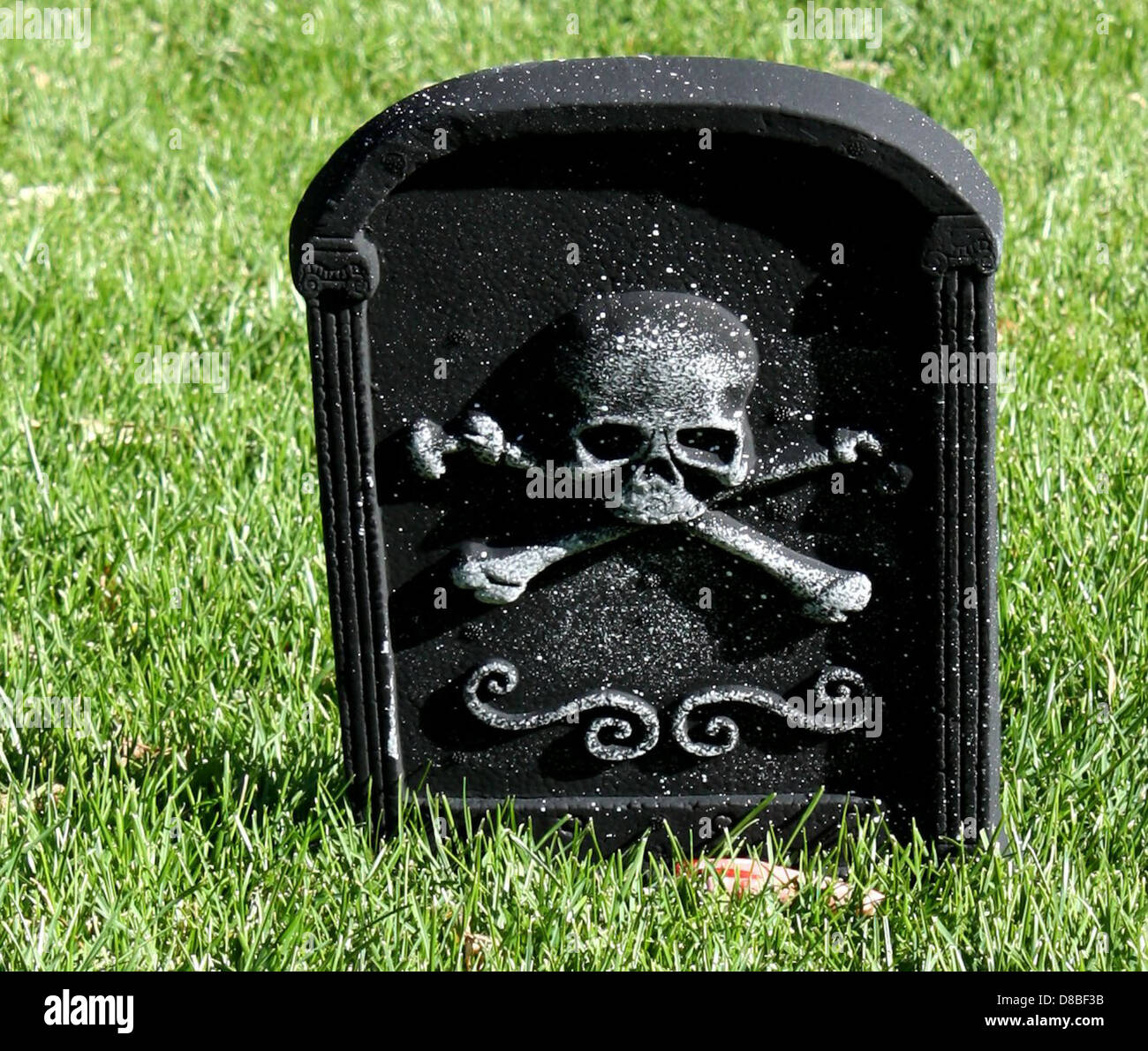 A Halloween-themed headstone decoration in a yard. The tombstone is ...