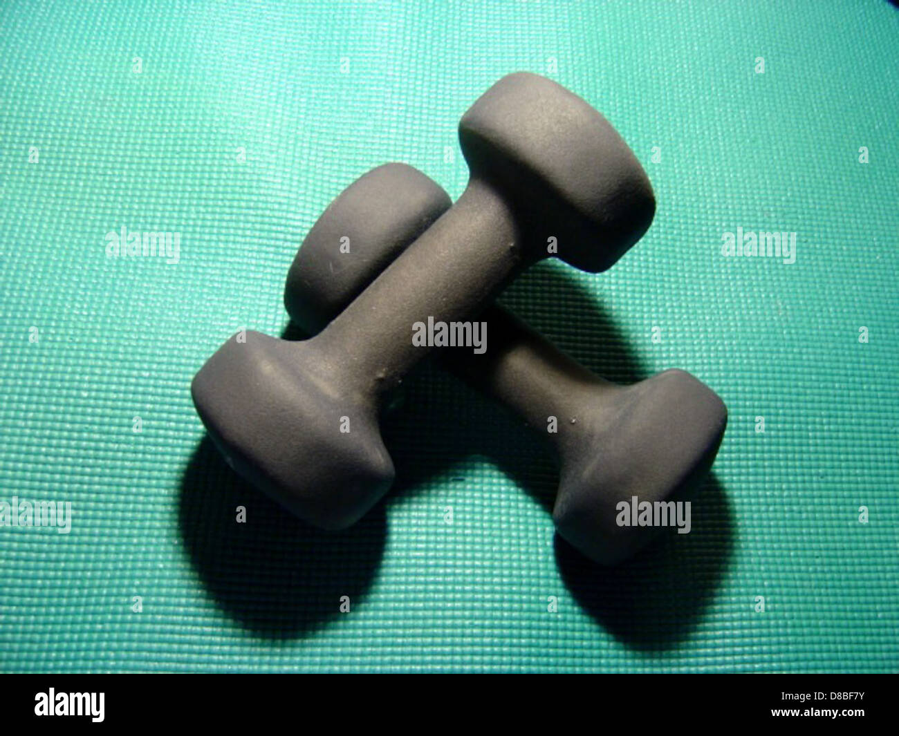 A pair of hand weights placed on a workout mat, ready for exercise. The ...