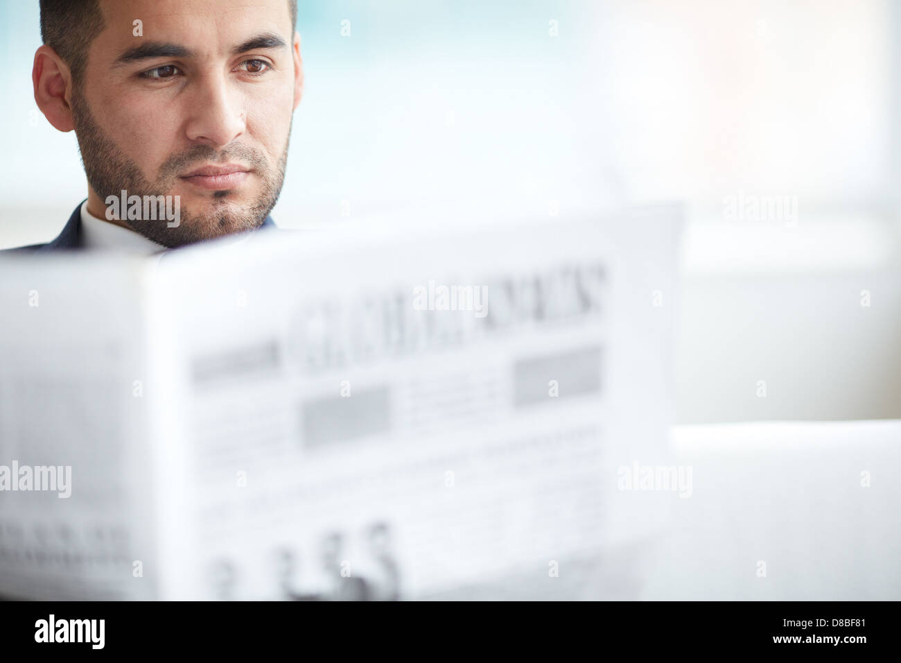 A young serious businessman reading newspaper Stock Photo - Alamy