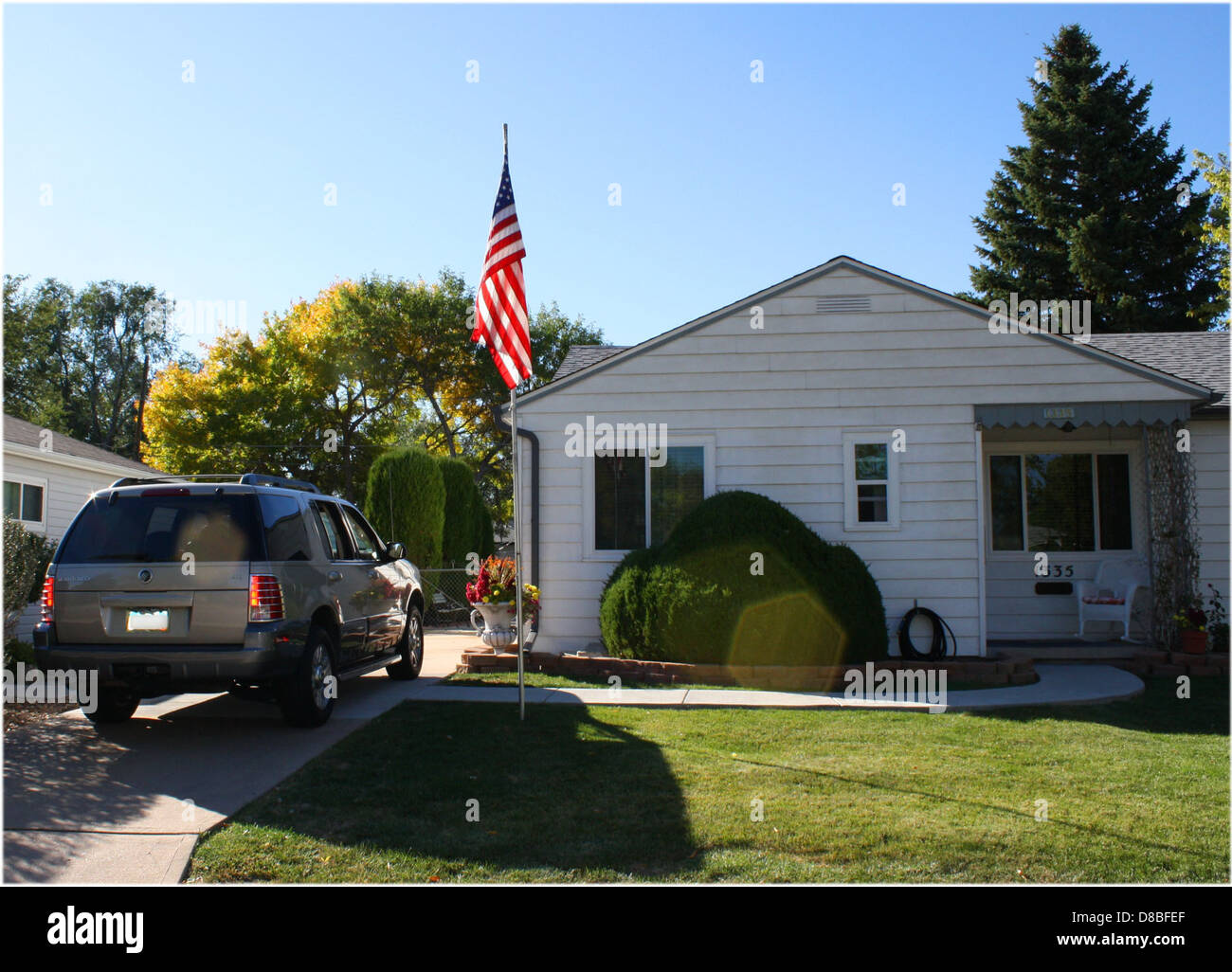 A house with an American flag displayed in front and an SUV parked in ...