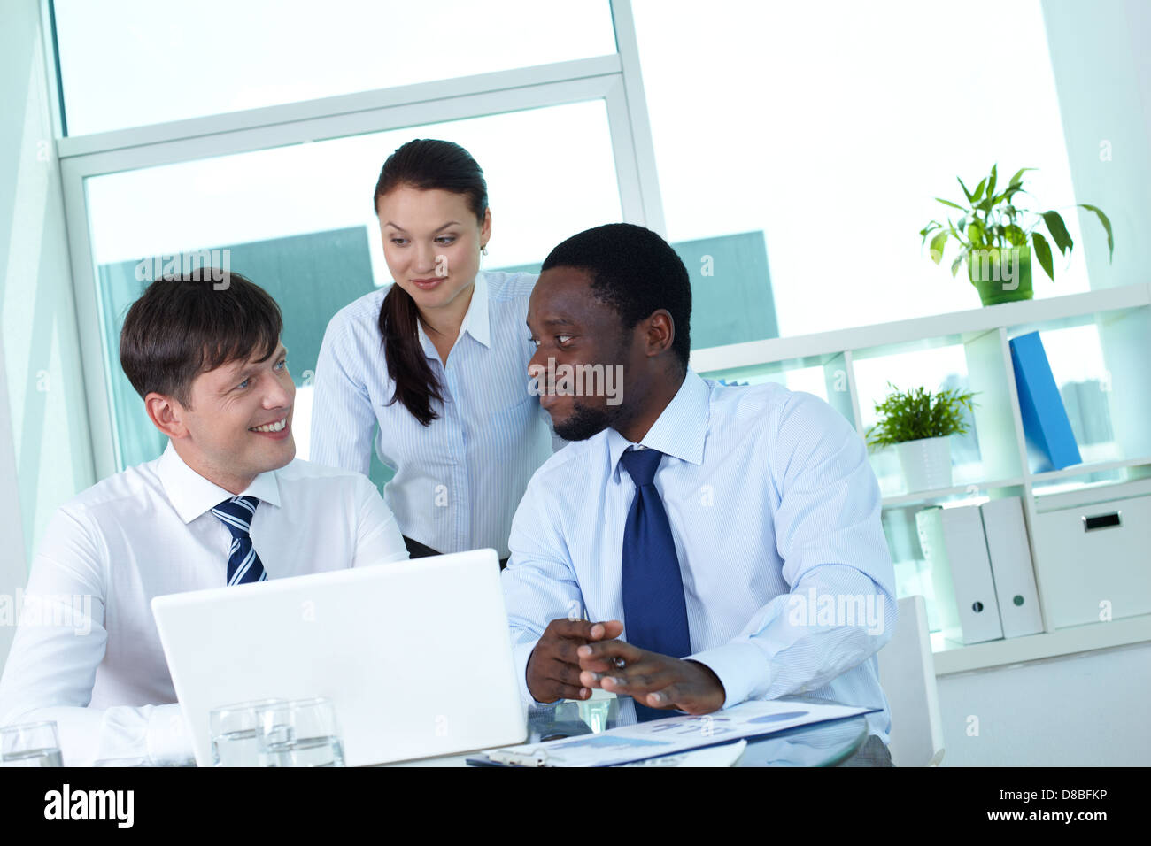 Three colleagues talking while working with laptop at meeting Stock ...