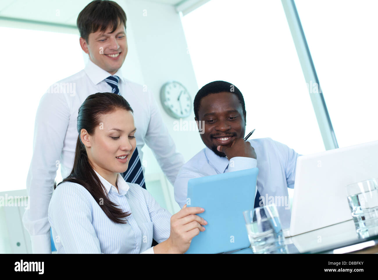 Male colleagues listening to young employee making electronic ...