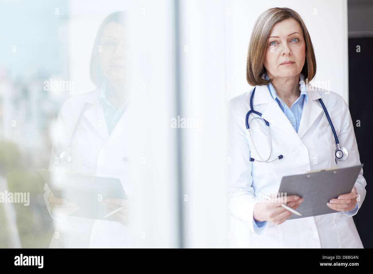 Portrait of pretty female practitioner with clipboard looking at camera ...