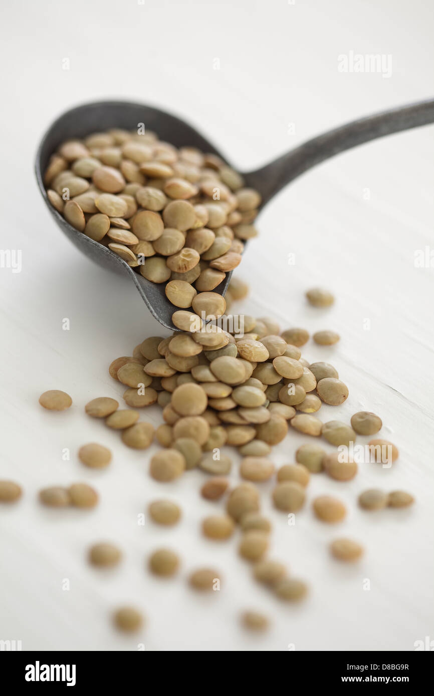 Green lentils spilling out of a ladle on to a white wood surface Stock ...
