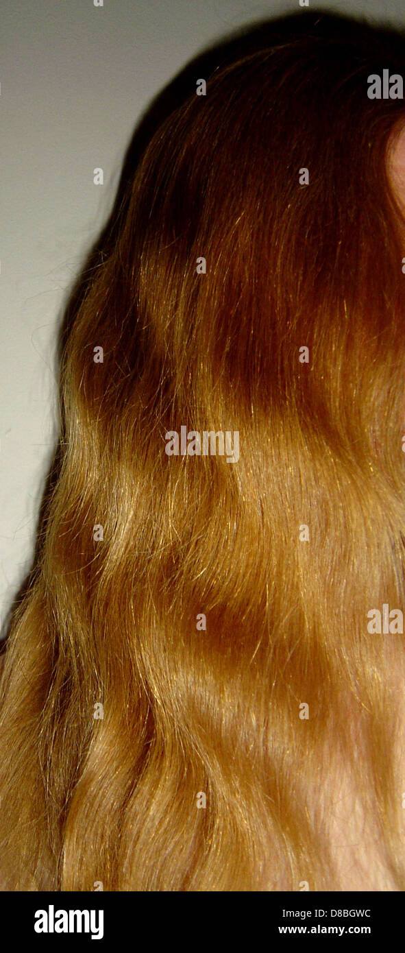 A close-up of long, flowing red hair. The hair shines with a vibrant ...