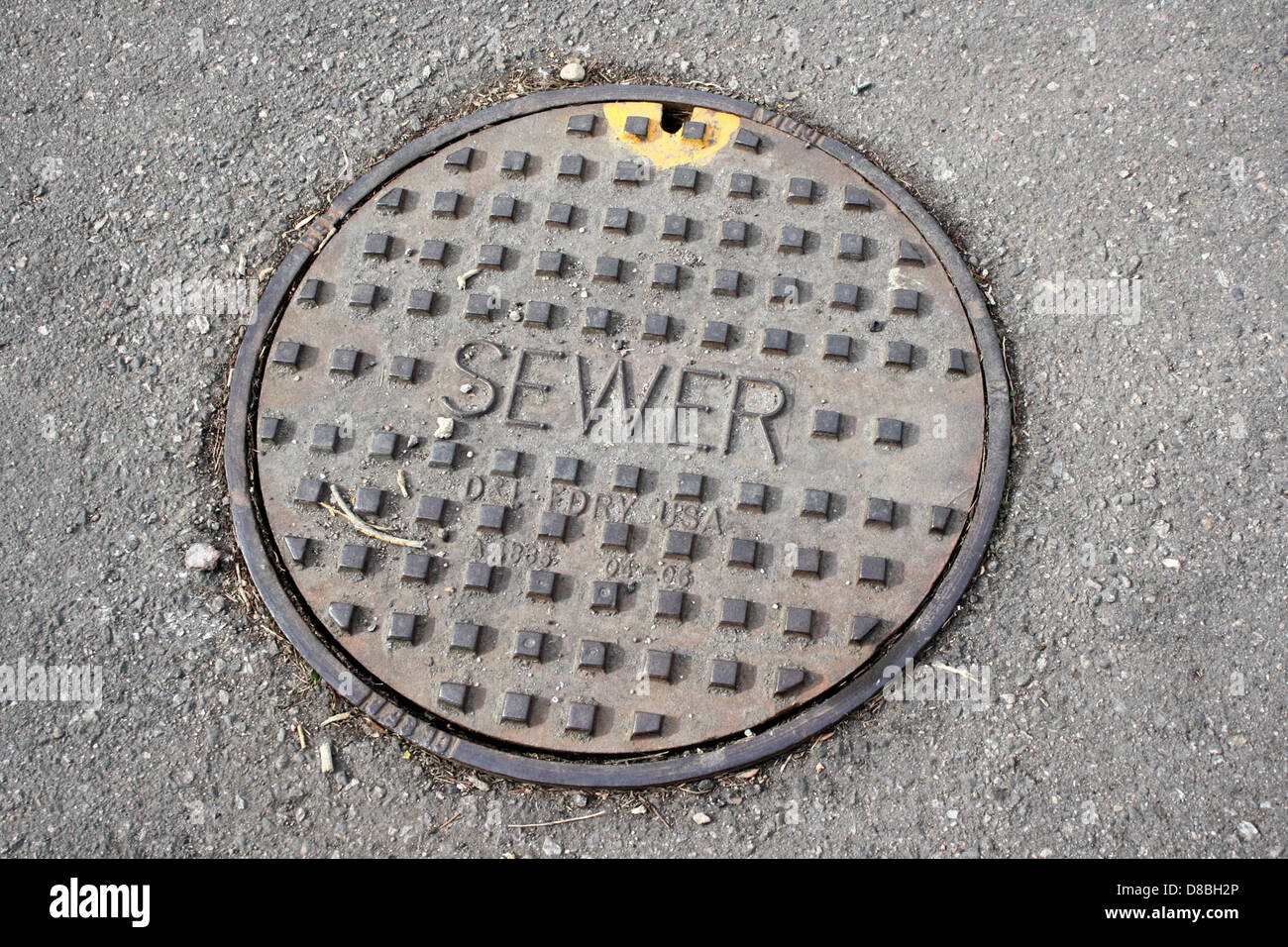 A detailed image of a manhole cover on a street. The photo emphasizes ...