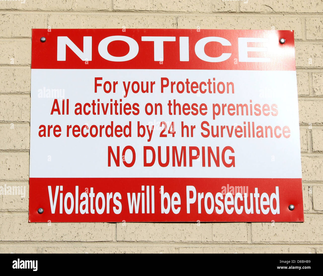 A clear 'No Dumping' sign stands prominently in an outdoor area ...