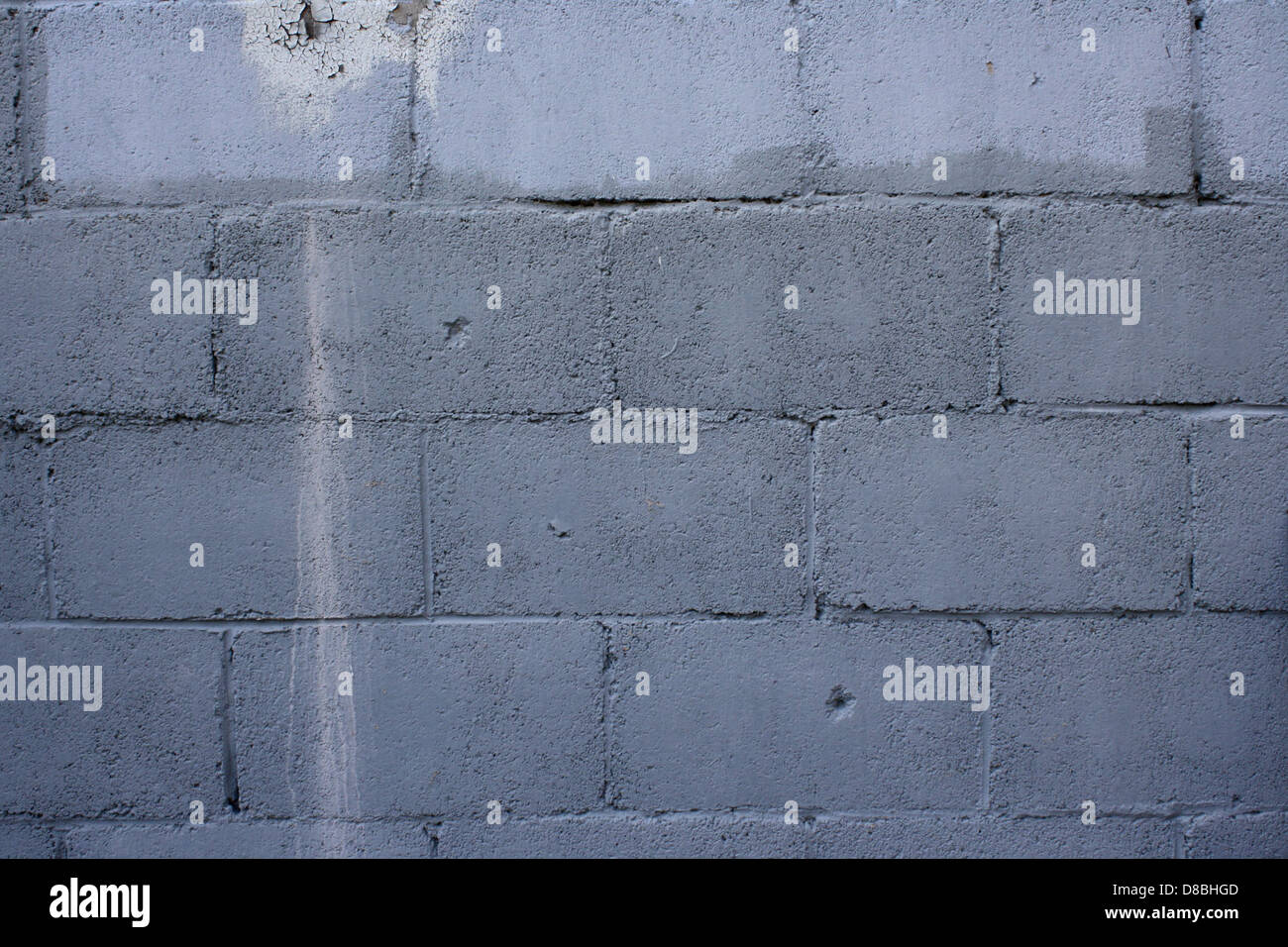 This image features a close-up of an old cinder block wall painted gray ...