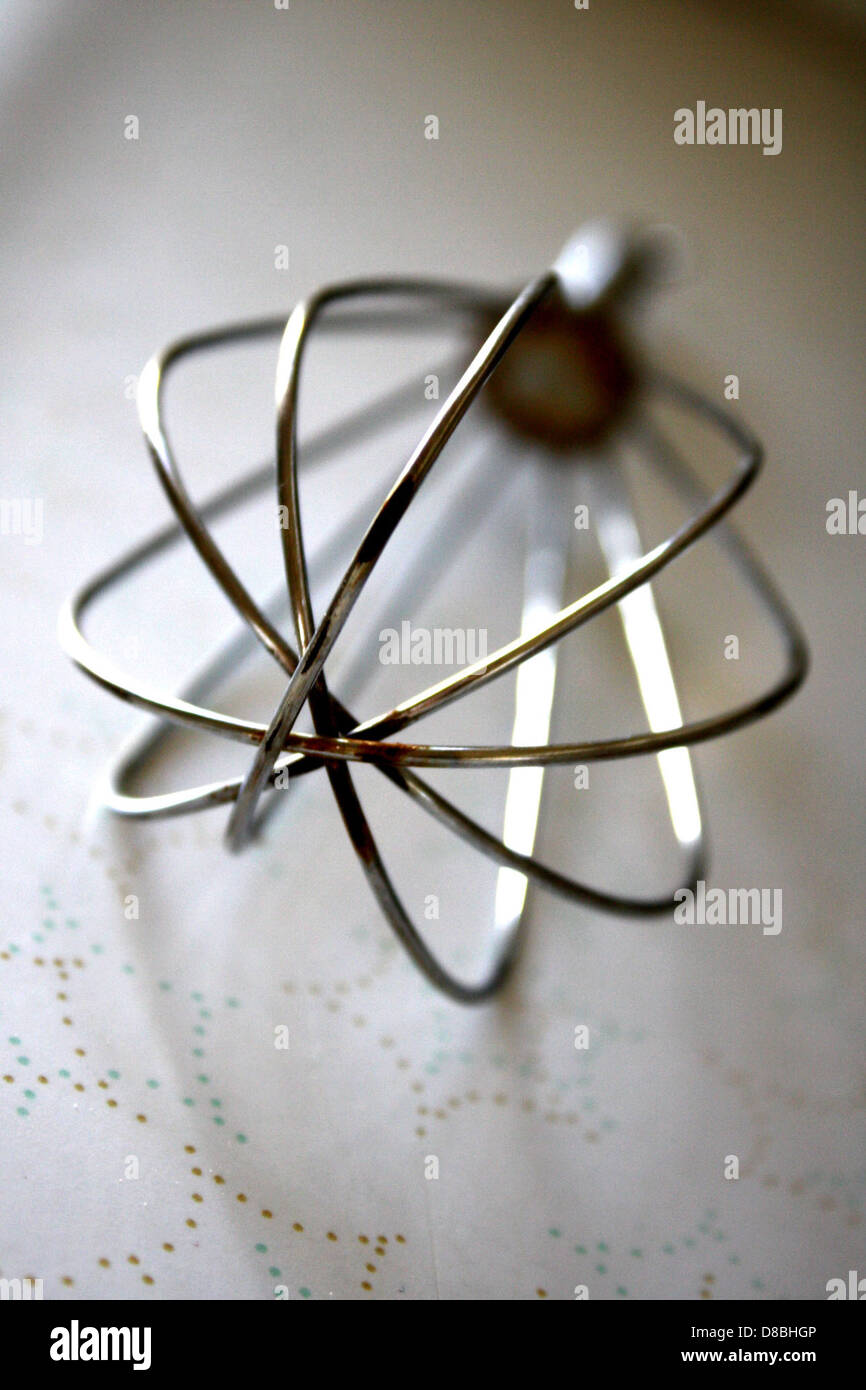 This image features an old kitchen whisk, showing signs of rust due to ...