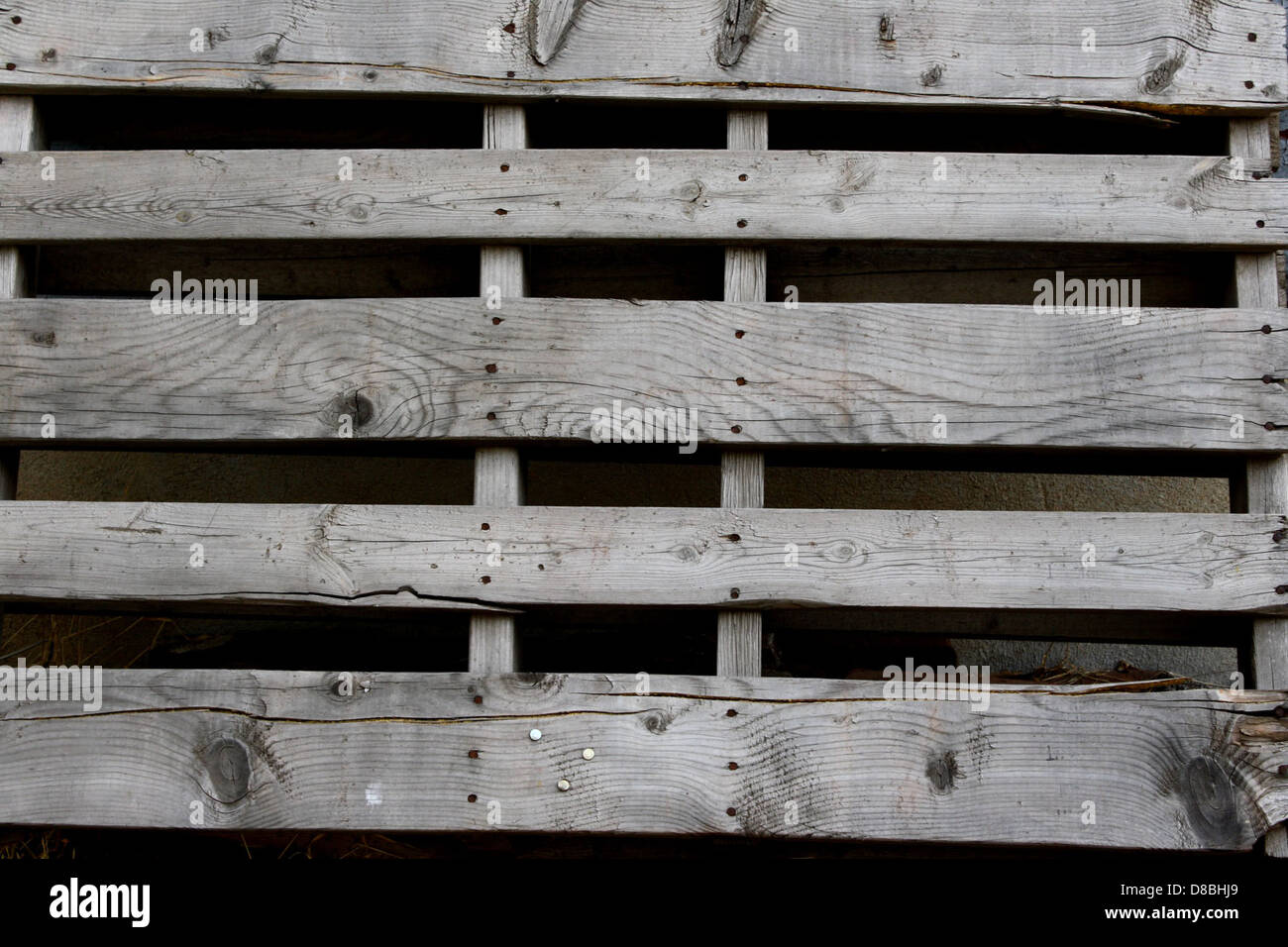 A close-up shot of an old, weathered wooden pallet. The worn wood shows ...