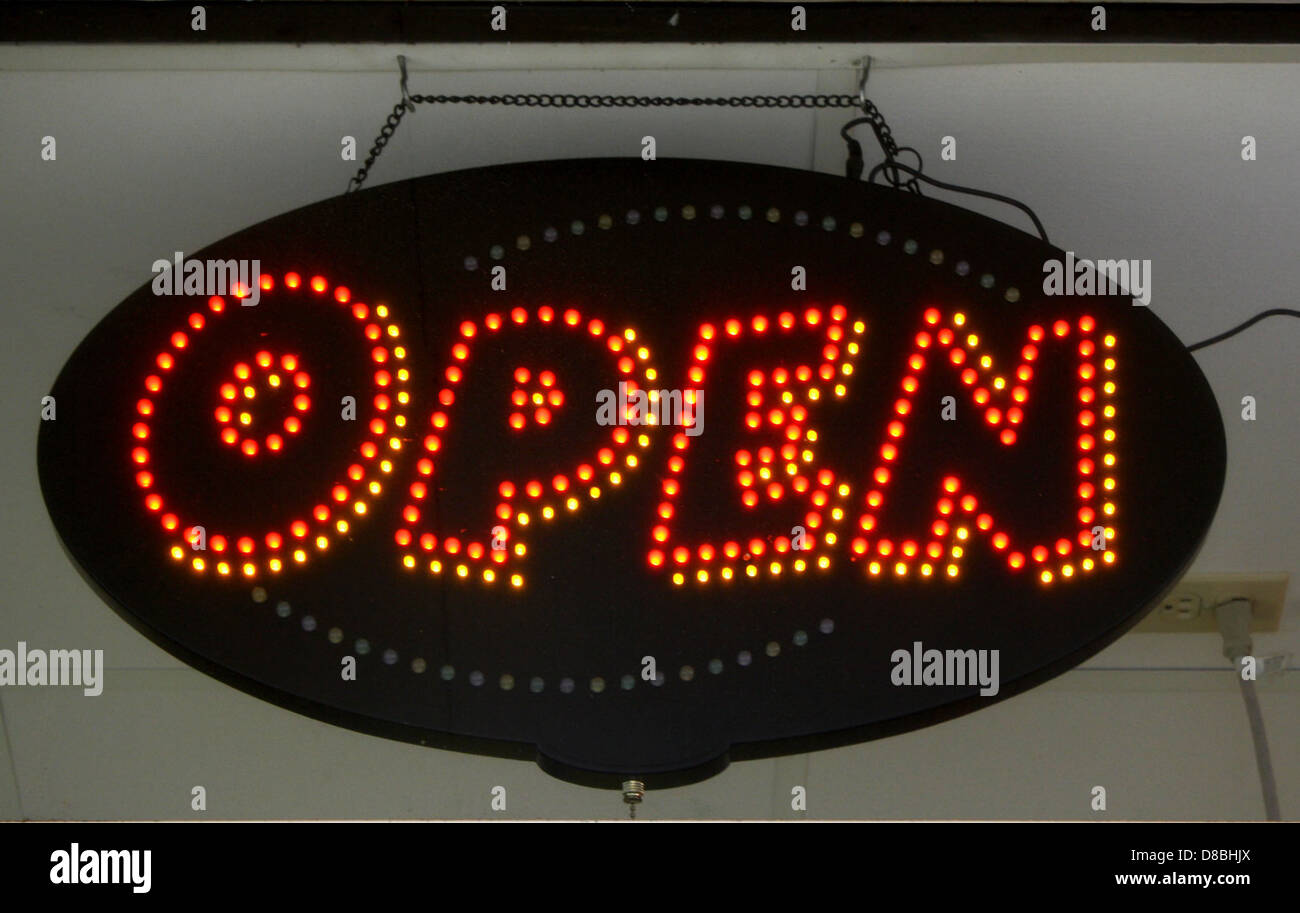 A classic 'Open' sign lit up in a storefront window, signaling that the ...