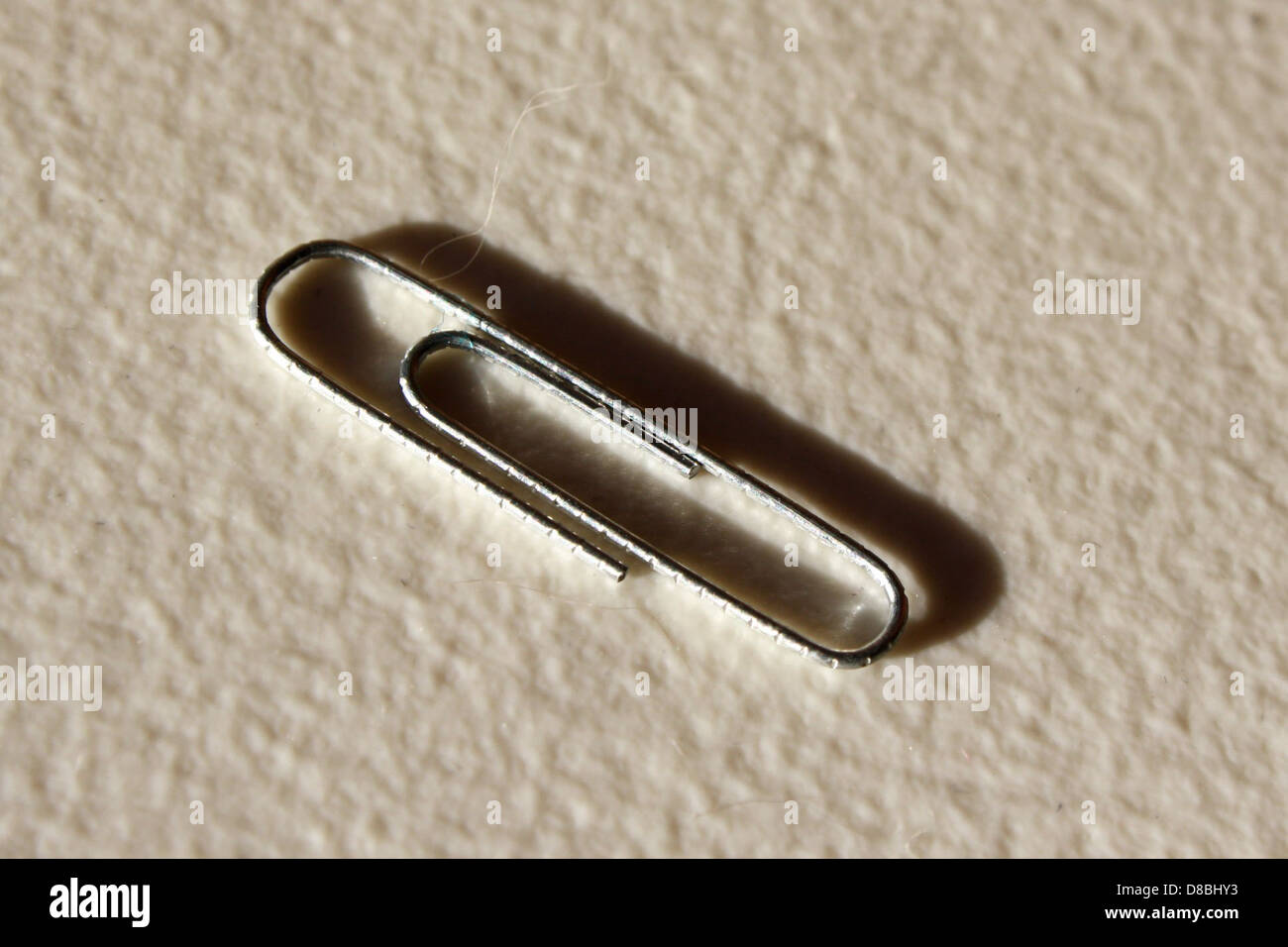 A simple metal paper clip used for holding sheets of paper together. It ...