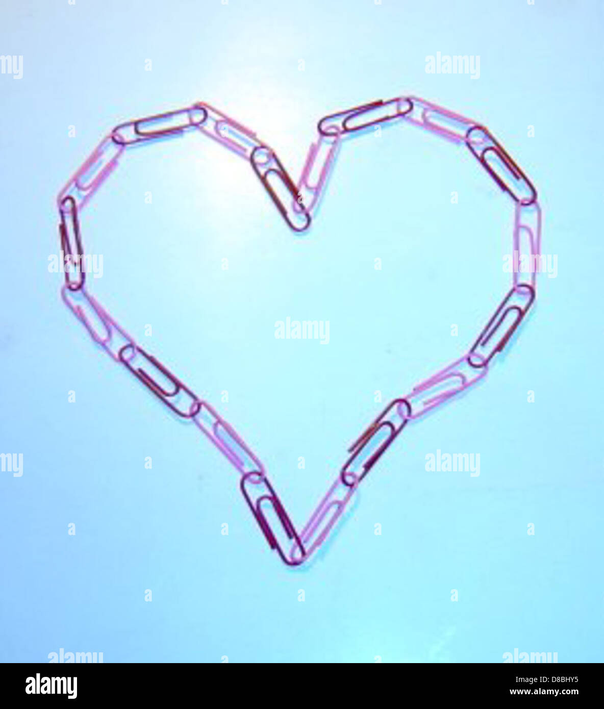 A paper clip shaped like a heart, sitting on a flat surface. The heart ...