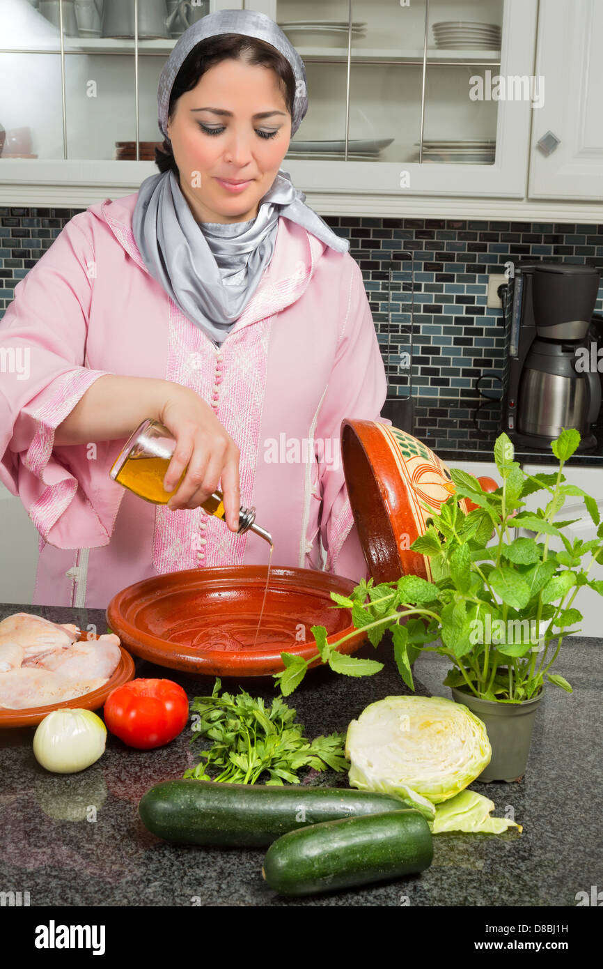 Traditional Moroccan immigrant woman in Europe adding olive oil to her ...