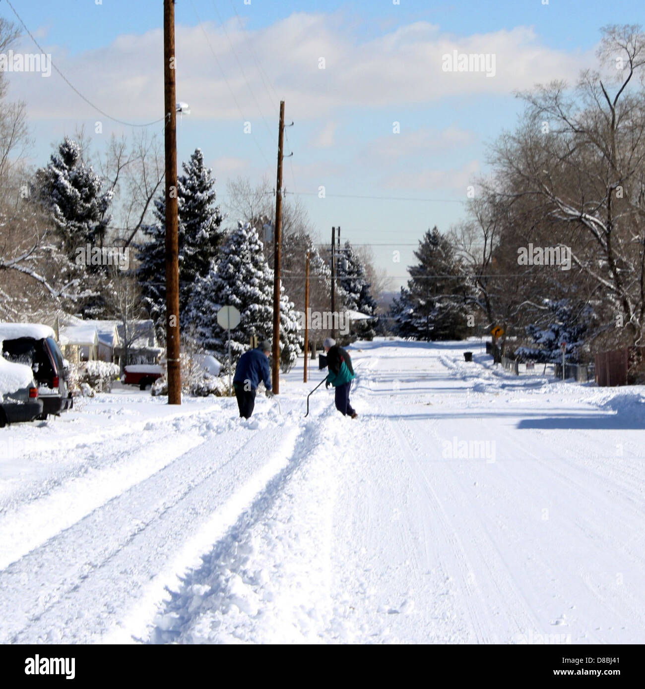 People are seen shoveling snow from a sidewalk after a winter storm ...