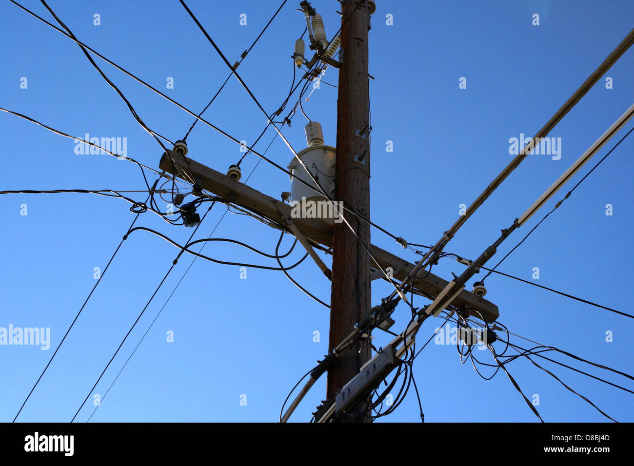A telephone pole with power lines stretches across a clear sky, with a ...