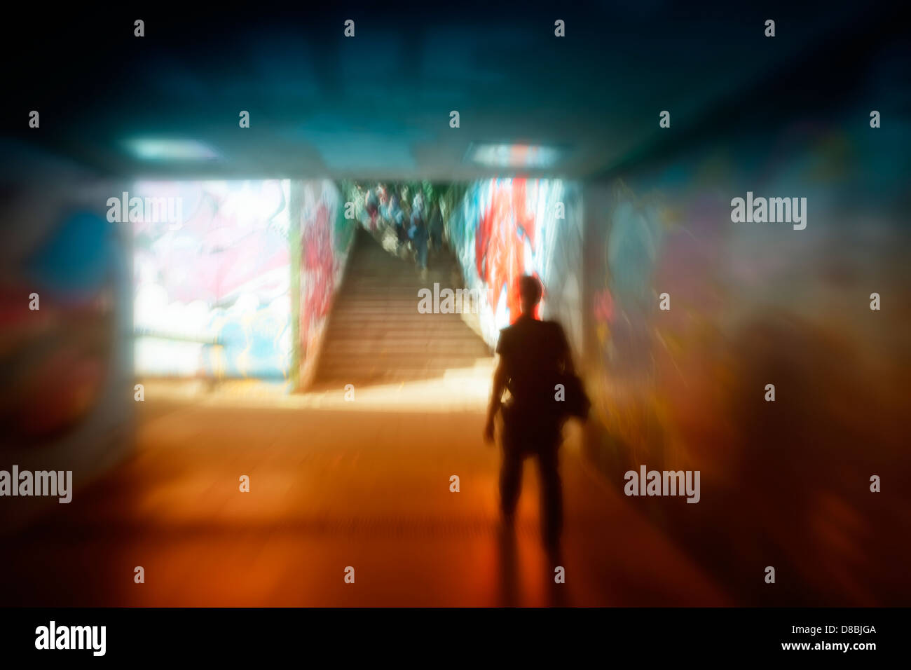 A man walking in a dark tunnel with graffiti, symbolic image for panic ...