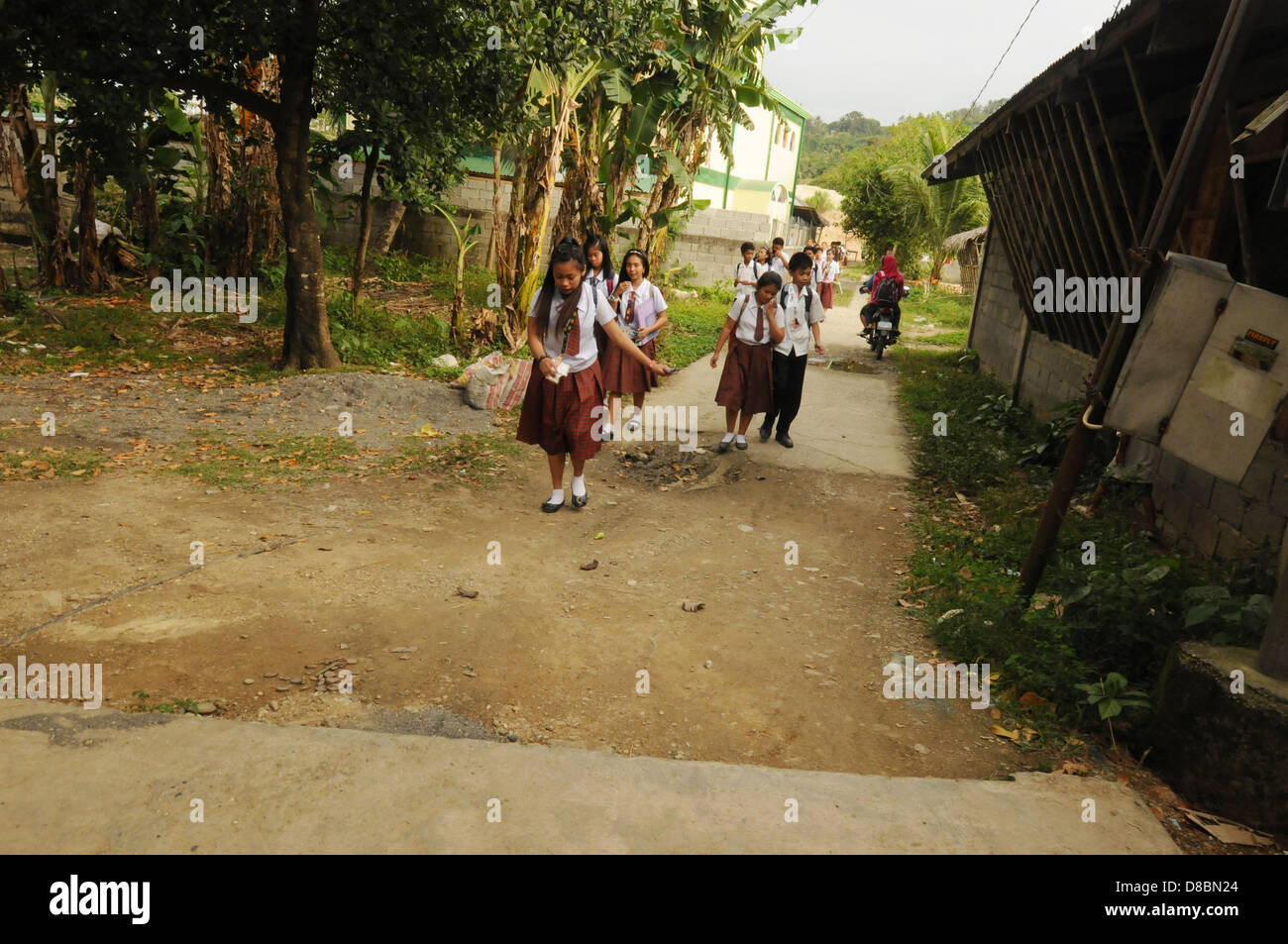 Filipino schoolchildren walk along the street in the coastal town of ...