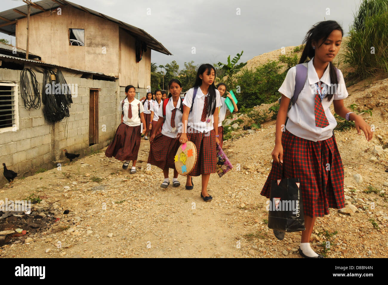 Filipino schoolchildren walk along the street in the coastal town of ...