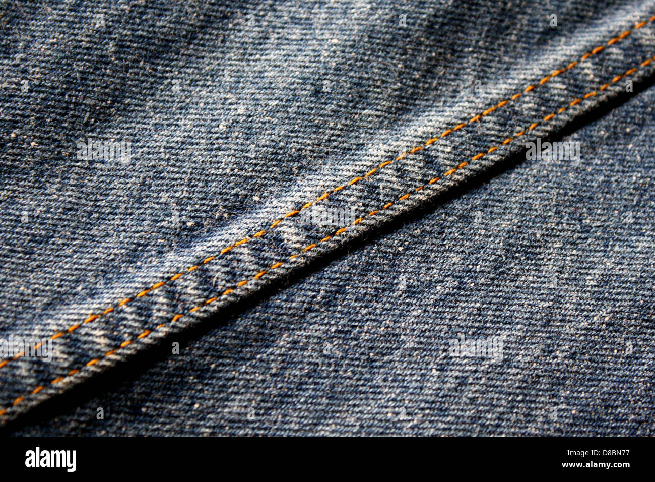 This close-up photograph shows the seam of a pair of denim blue jeans ...