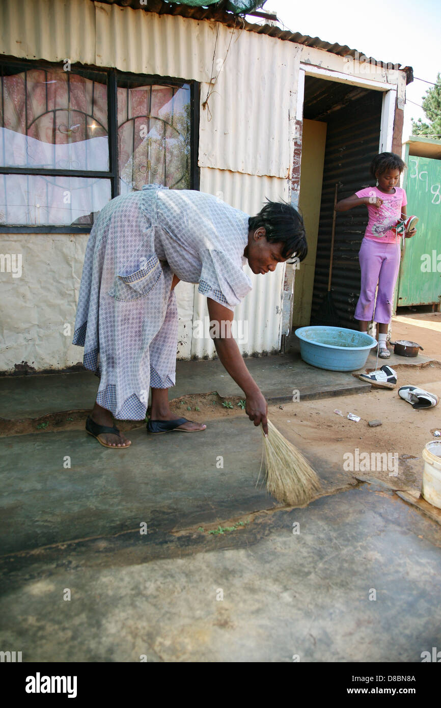 An African woman sweeps the doorstep of her tin shack home Stock Photo ...