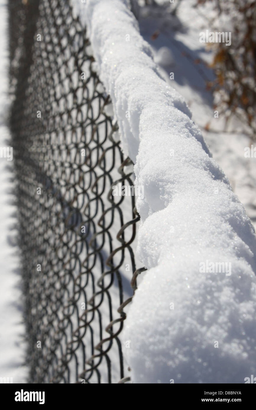 This image shows a chain link fence covered with a layer of snow ...