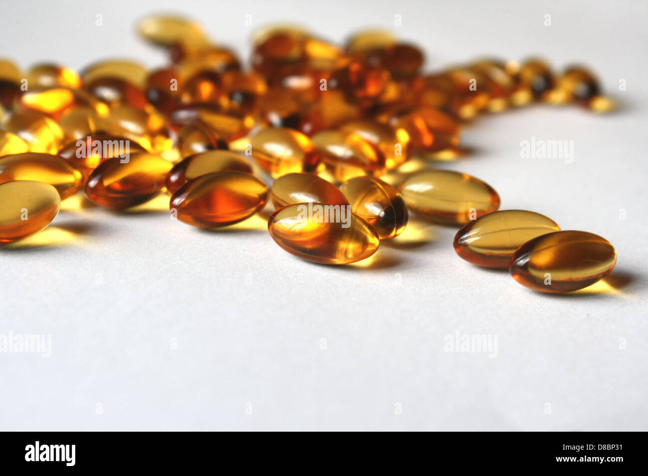 This image shows a close-up of soft gel vitamin pill capsules, commonly ...
