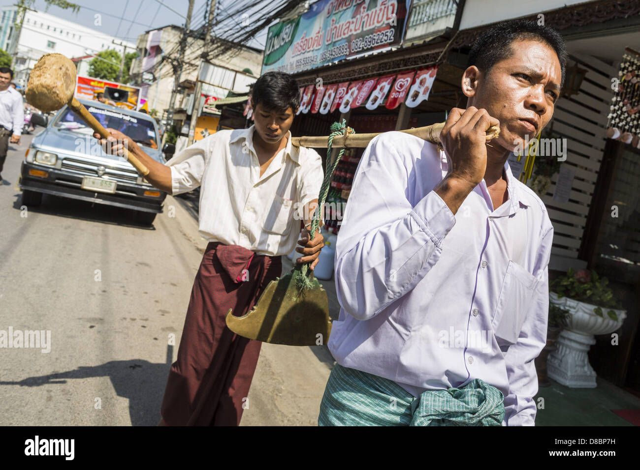 Mae Sot, Tak, Thailand. May 24, 2013. Burmese men carry a prayer gong ...