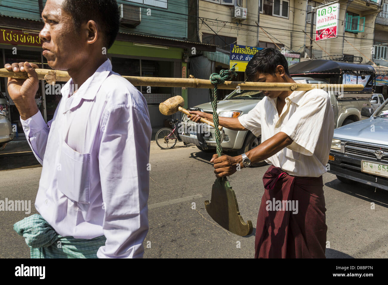 Mae Sot, Tak, Thailand. May 24, 2013. Burmese men carry a prayer gong ...