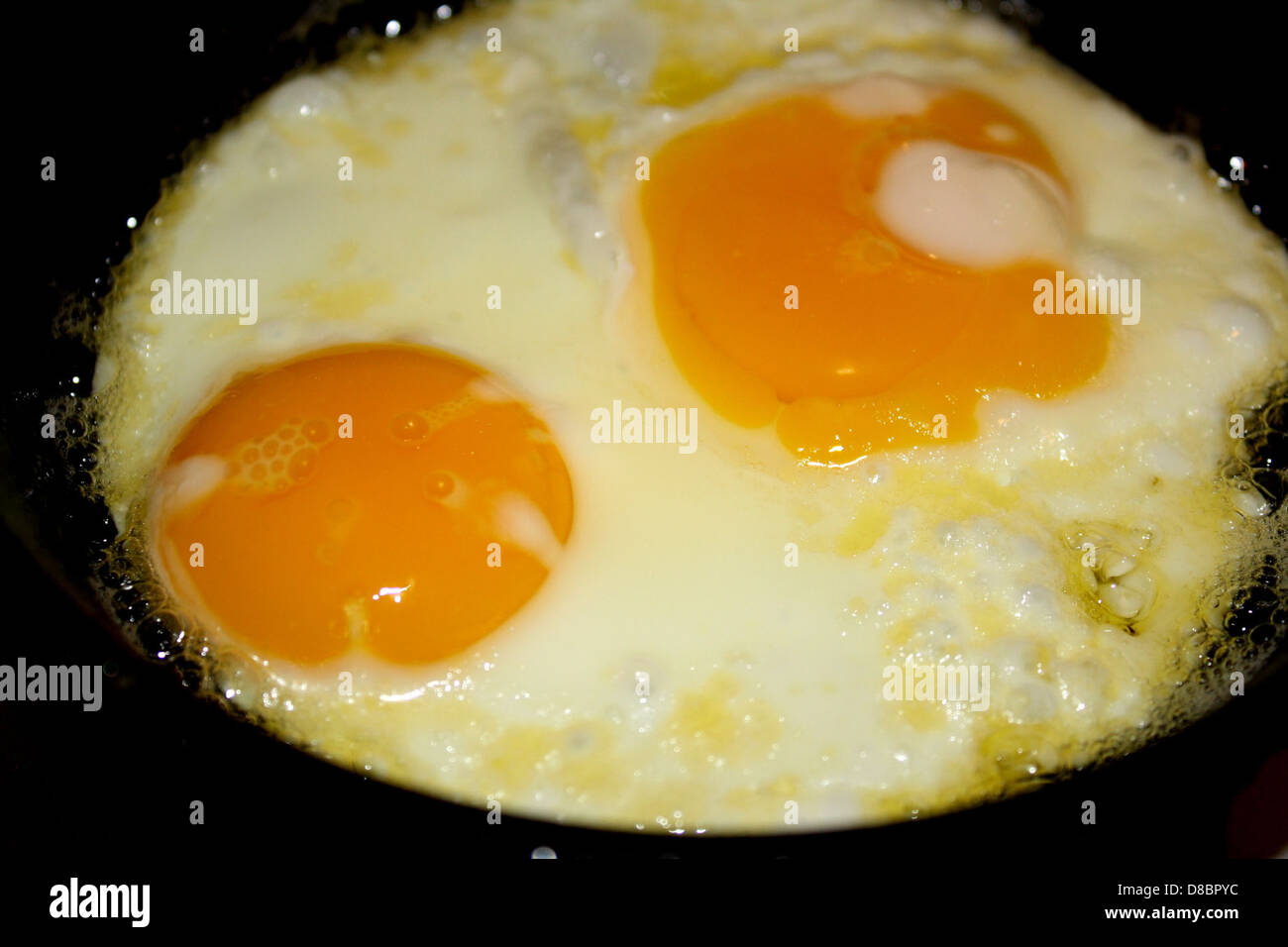 A close-up image of sunny side-up fried eggs, cooked to perfection with ...