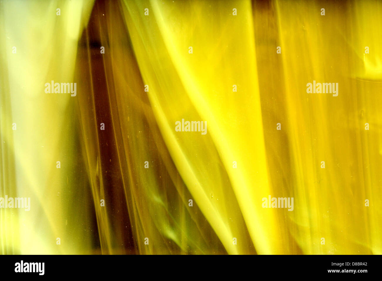 A close-up of swirled yellow glass, with its unique texture and vibrant ...