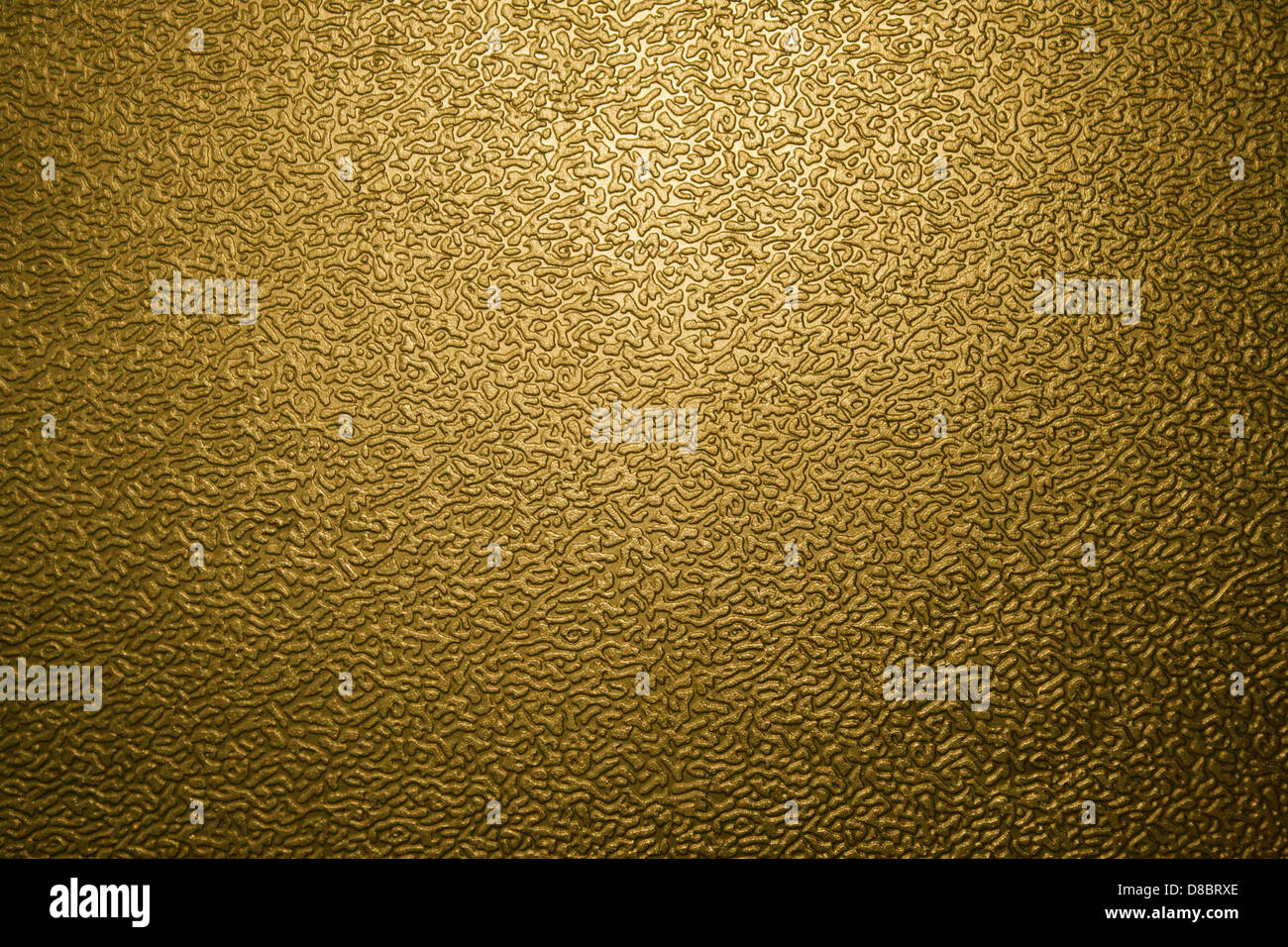 This close-up image shows the texture of a gold-colored plastic surface ...