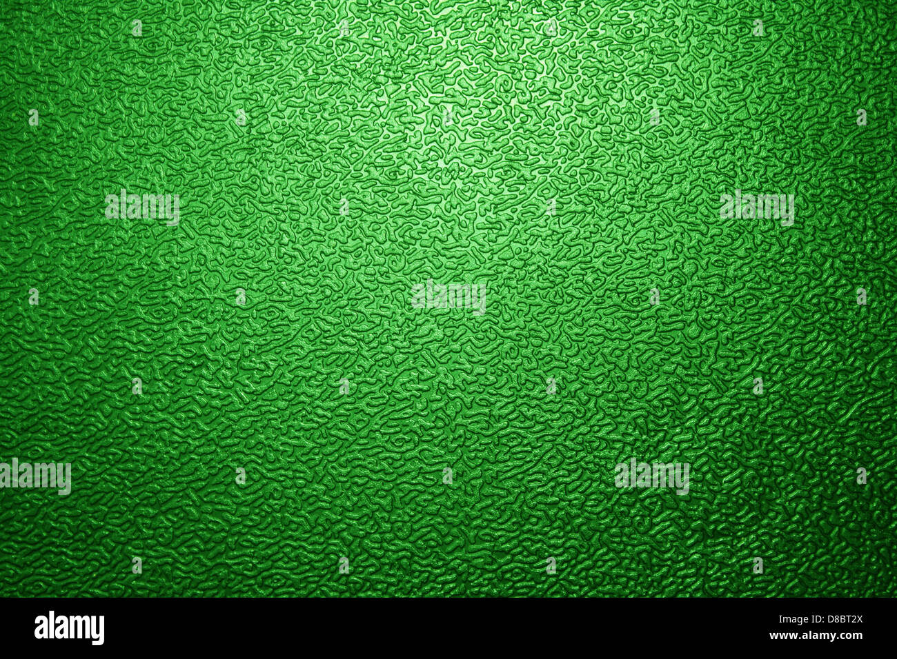 This close-up image focuses on a textured green plastic surface. The ...