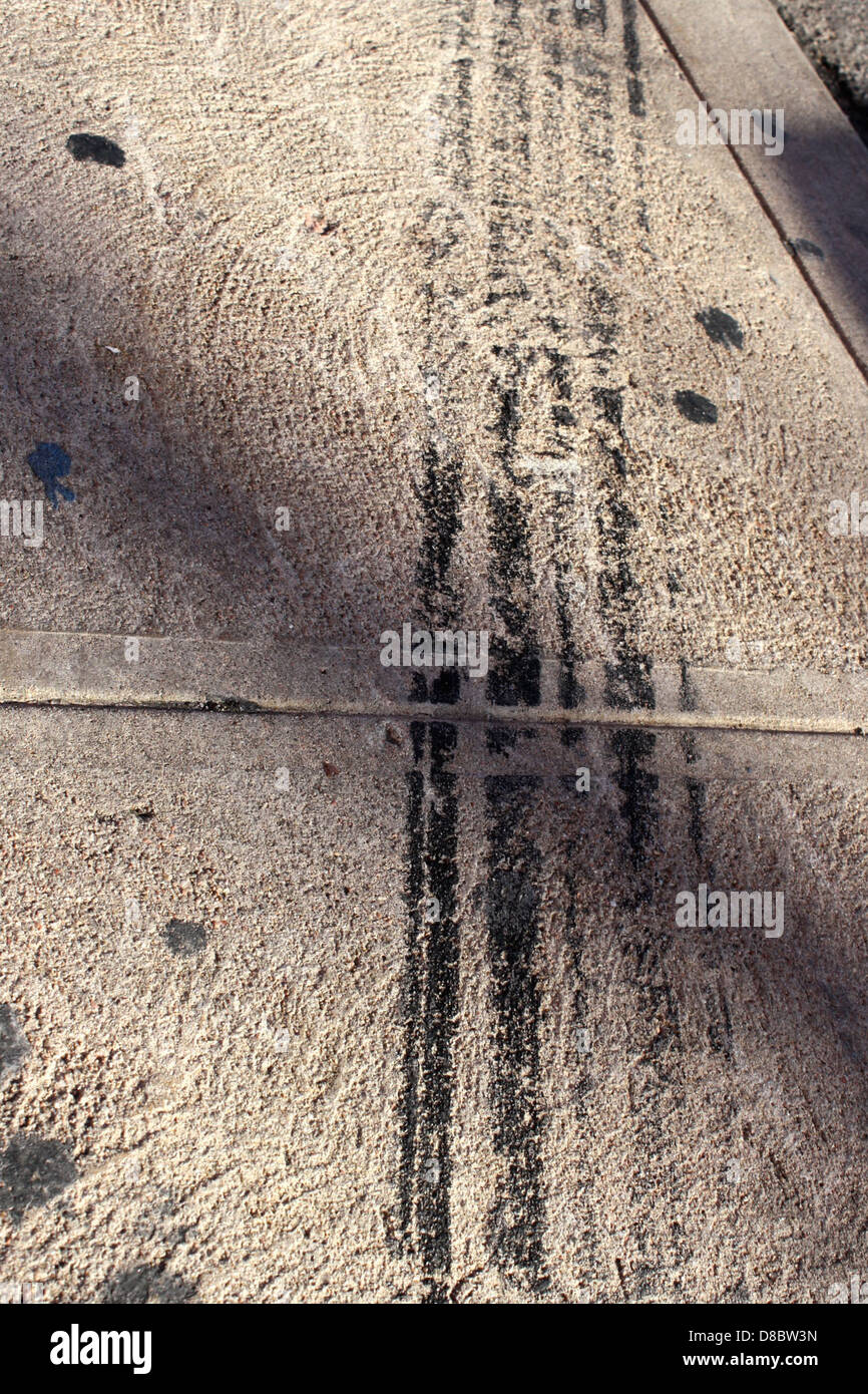 Visible tire skid marks streak across the sidewalk, showing the path of ...