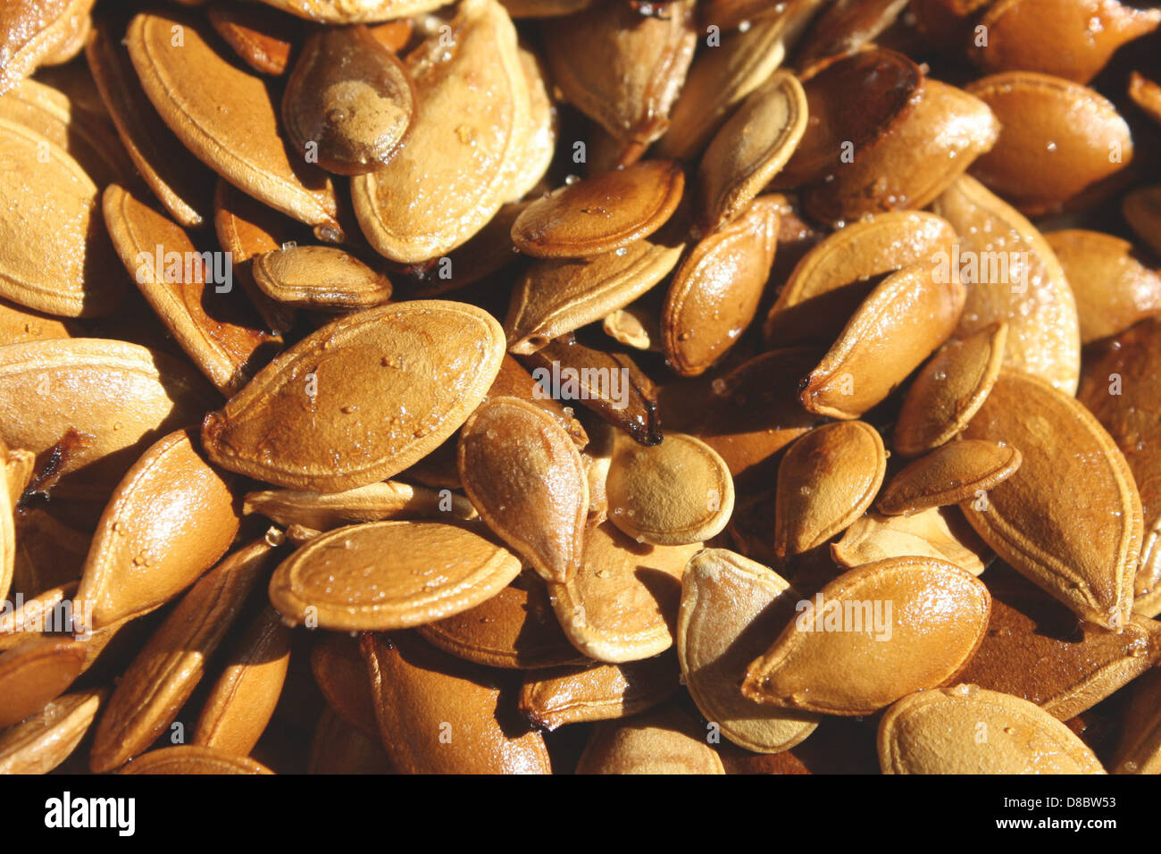 The image displays the texture of toasted pumpkin seeds, which have a ...