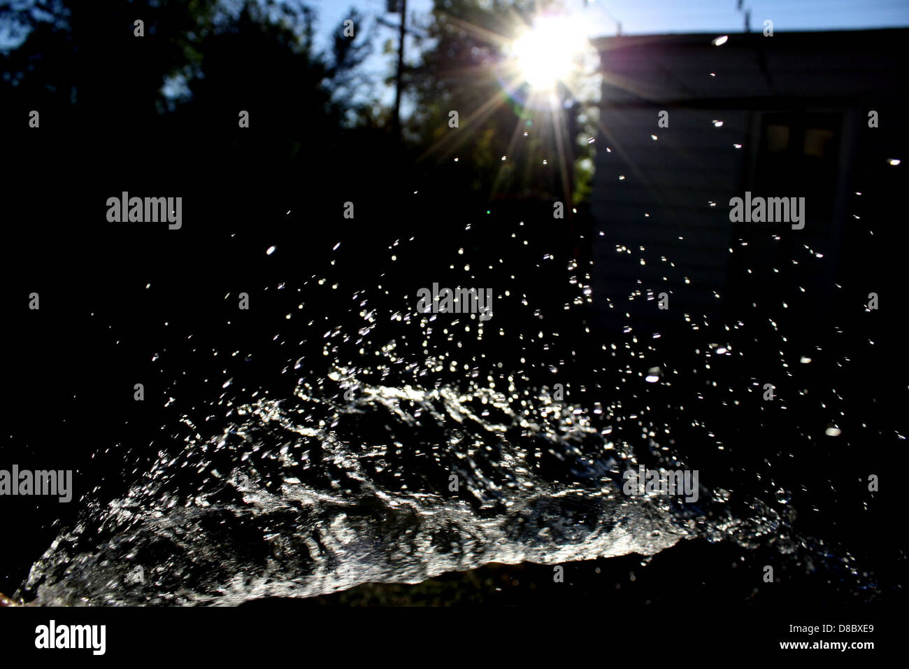 The image captures a water splash illuminated by sunlight, highlighting ...