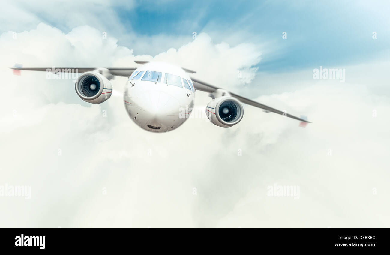 Passenger plane with cockpit and engines in front view flying high in ...