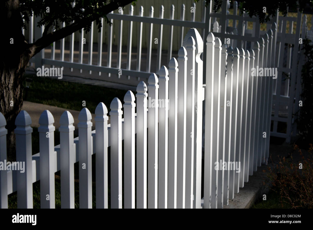 A traditional white picket fence standing in front of a house ...
